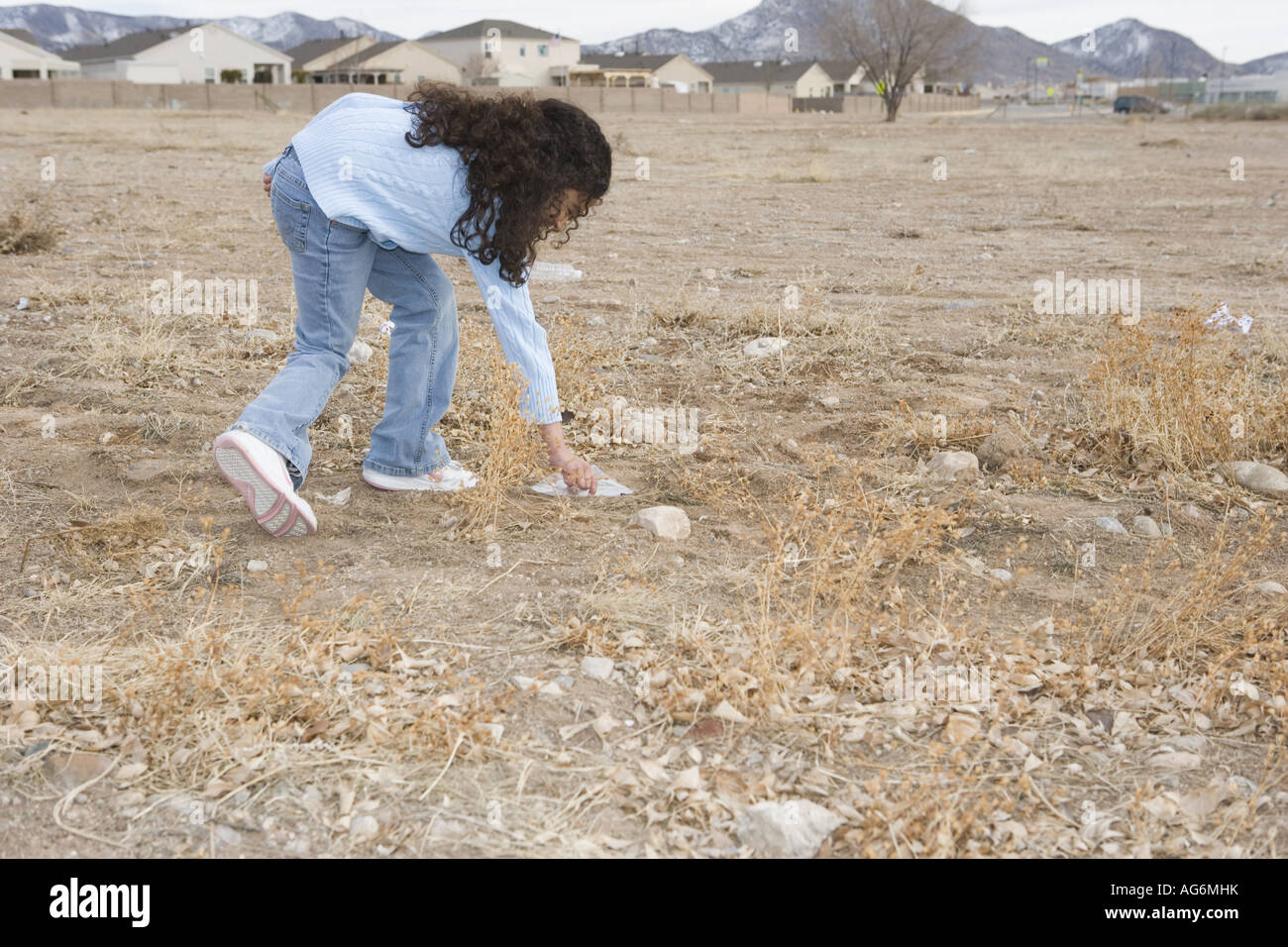 young girl picking up trash in suburban field, southwestern USA Stock ...