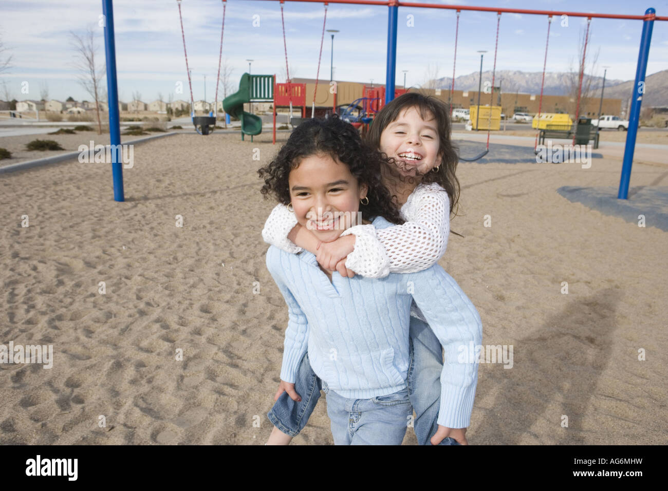 girl giving piggy back ride for sister on playground Stock Photo - Alamy