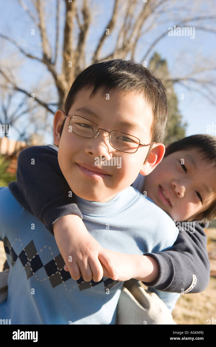 Japanese siblings smiling outdoors, piggyback ride in december Stock ...