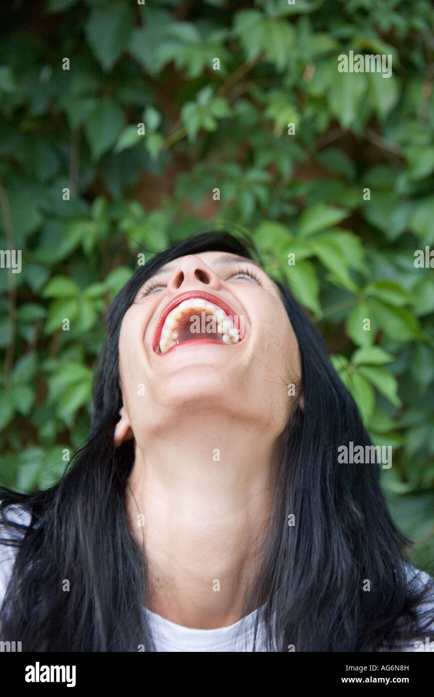 woman laughing looking up with green ivy background Stock Photo - Alamy