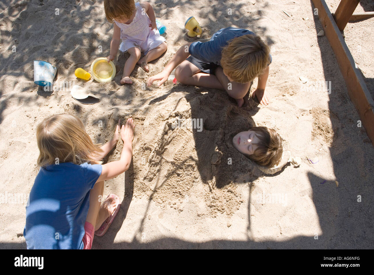 kids burying a friend in sand Stock Photo - Alamy