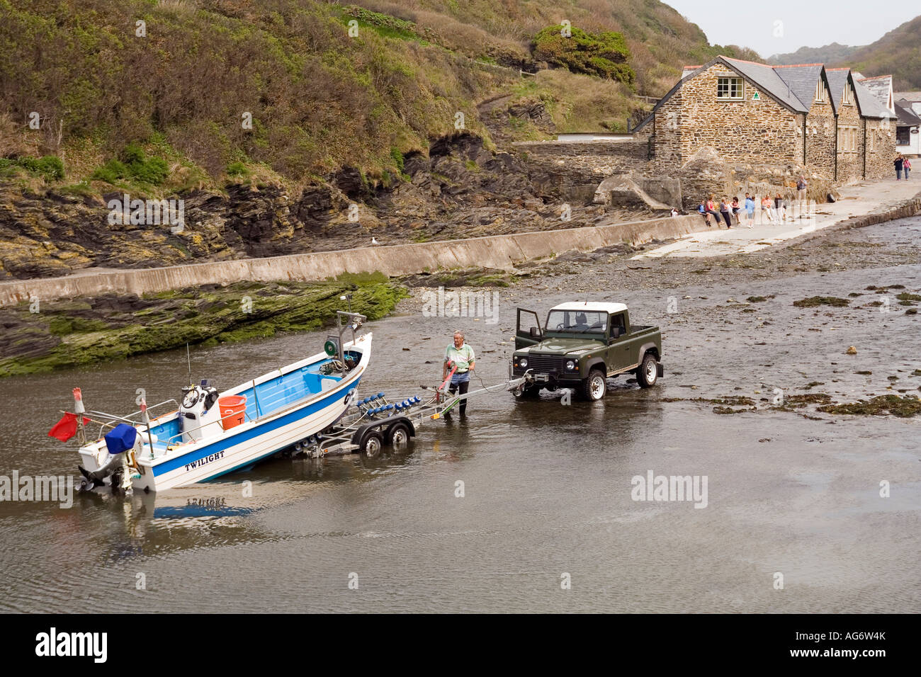 UK Cornwall Boscastle harbour man loading boat onto trailer at low tide ...