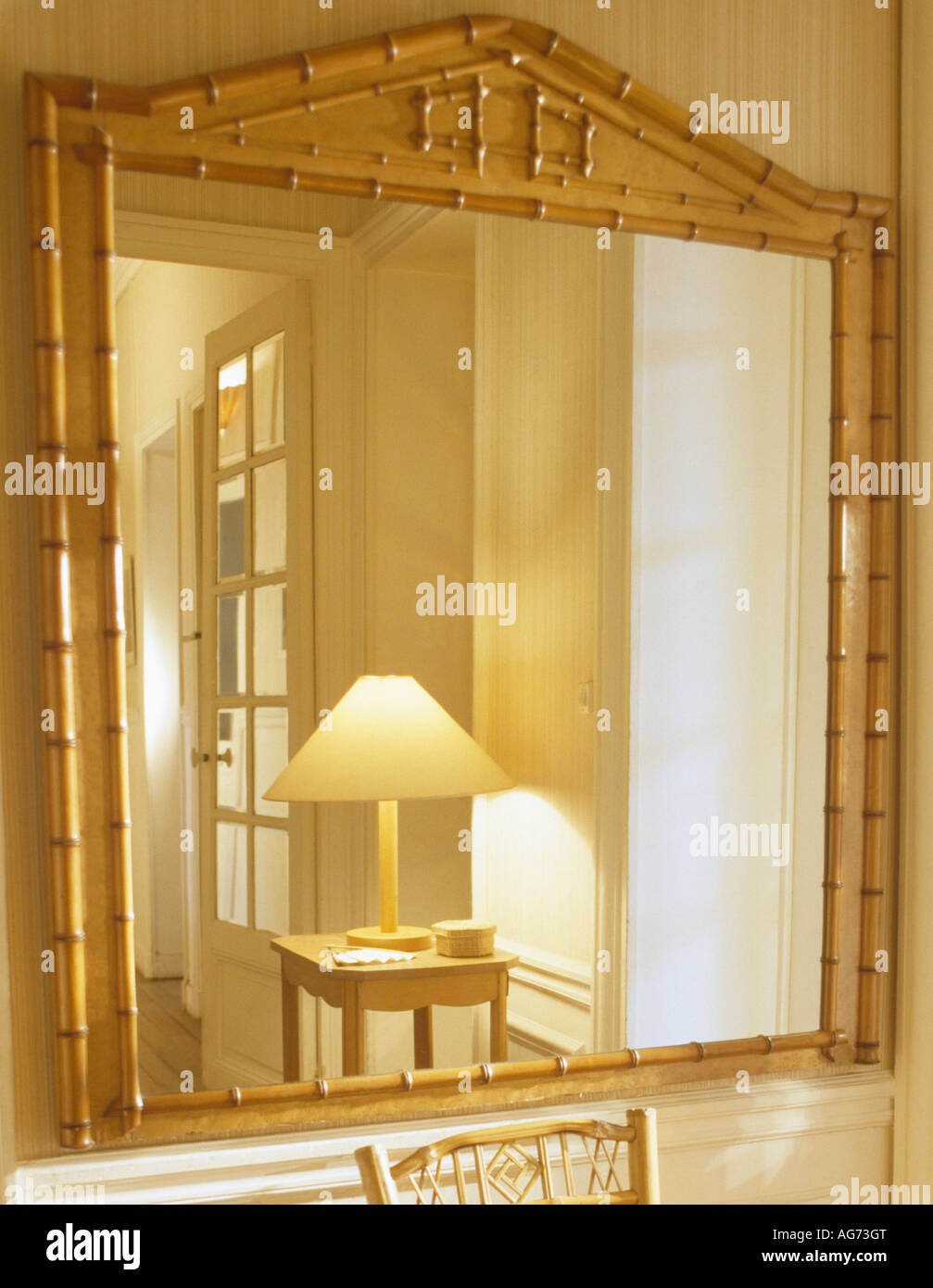 Lighted lamp on hall table reflected in bamboo mirror Stock Photo - Alamy