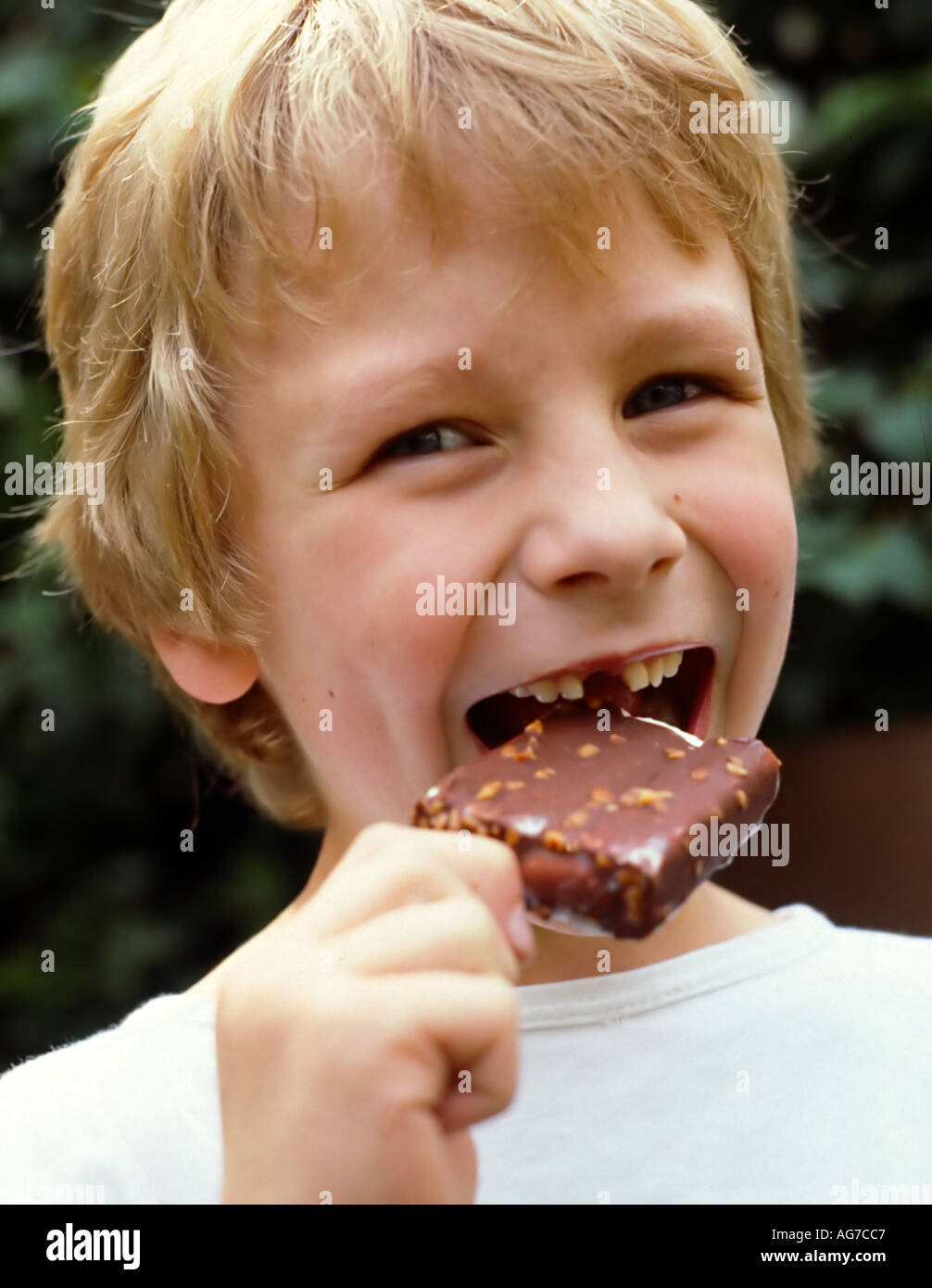 faire haired blonde boy with a cap between his teeth biting in an ice ...
