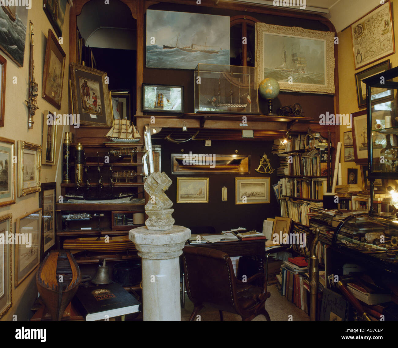 Sculpture on pedestal in French country study with pictures on the ...