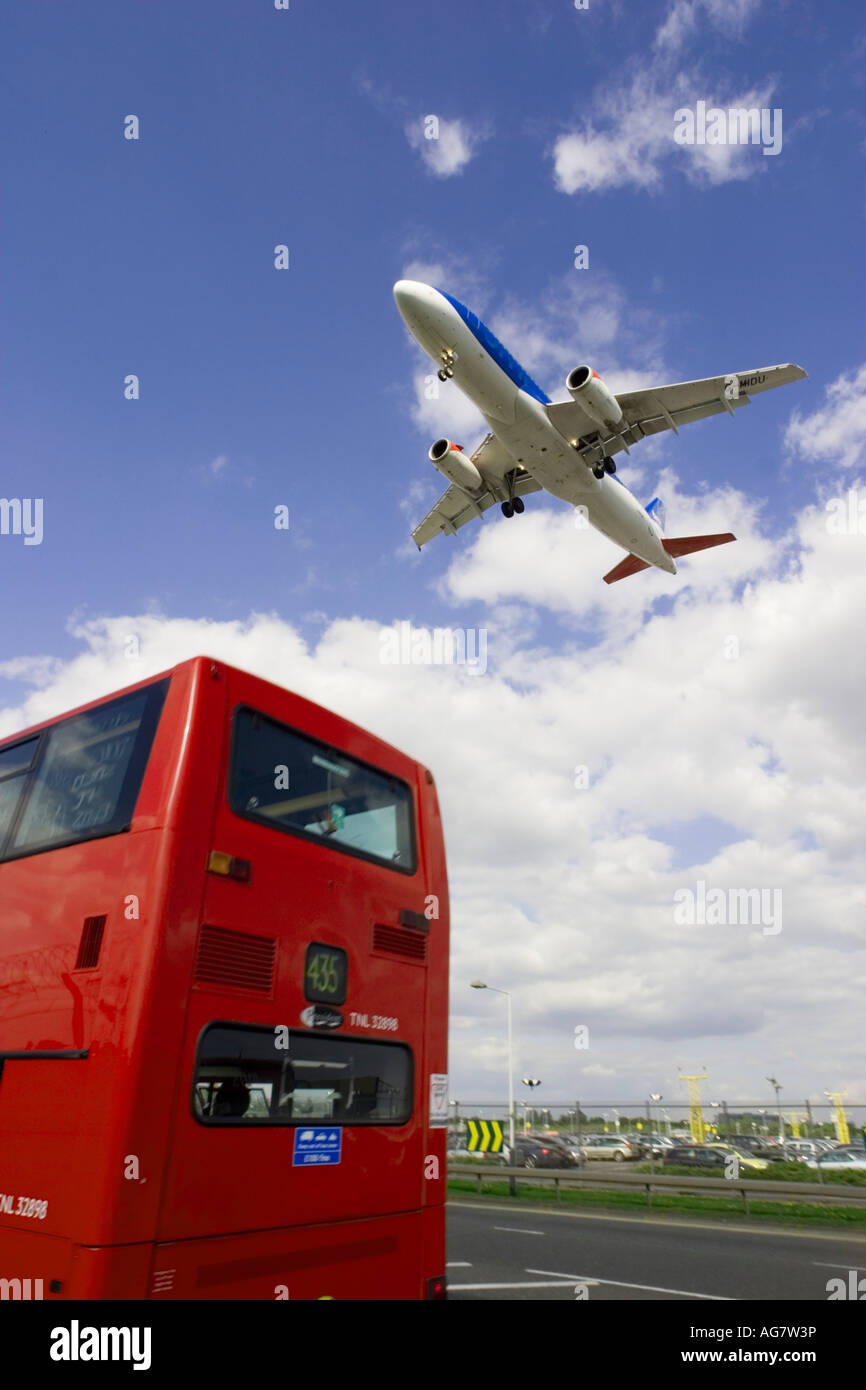 Plane flying above red bus Stock Photo - Alamy