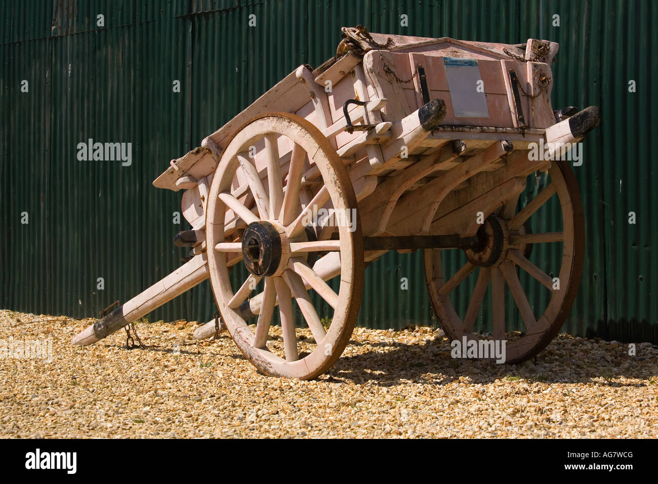 Wooden farm cart standing on gravel outside green corrugated iron bard ...