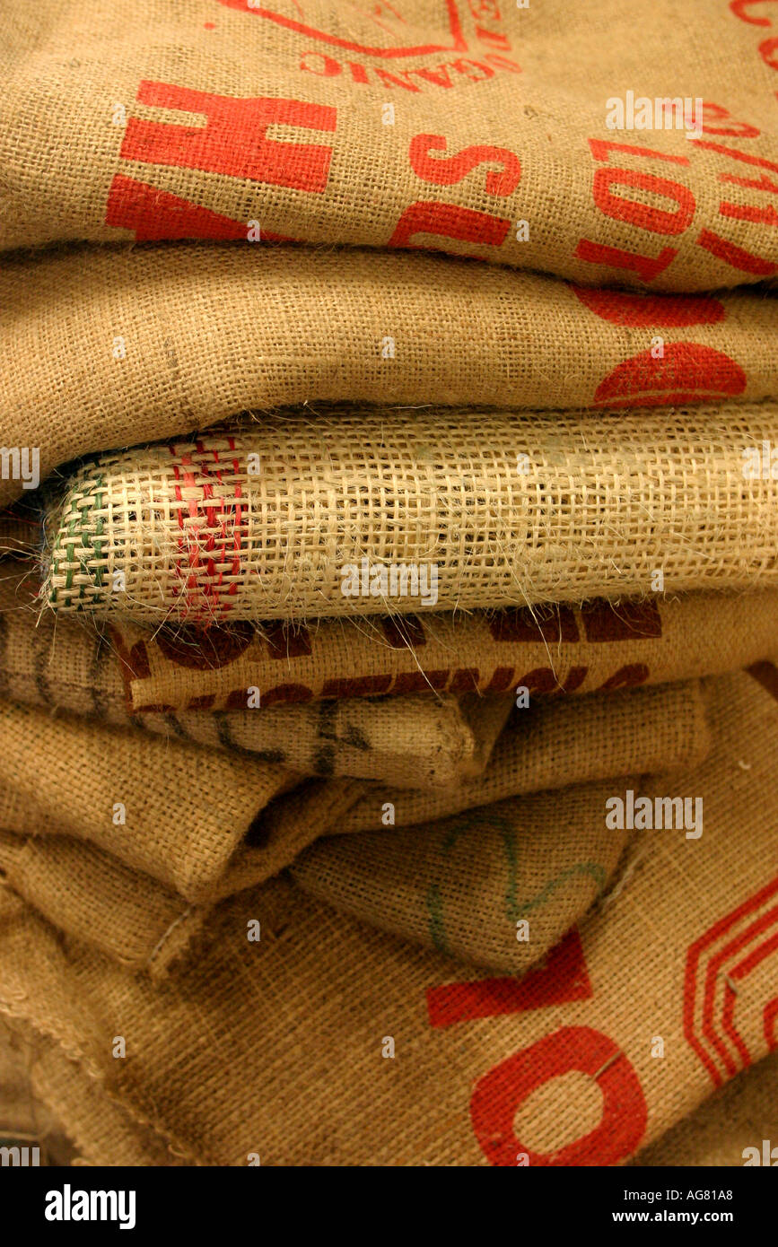 A pile of canvas coffee sacks containing the green beans sit at a ...
