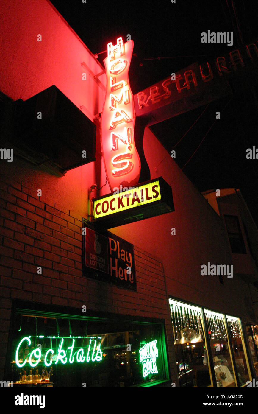A fluorescent pink signs for a bar glows along with a neon sign reading ...