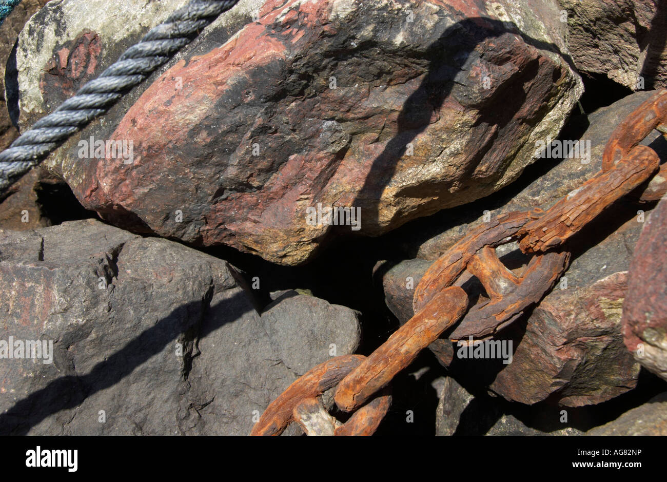 Mooring rope and rusty chain on harbour rocks Vila Nova de Milfontes ...
