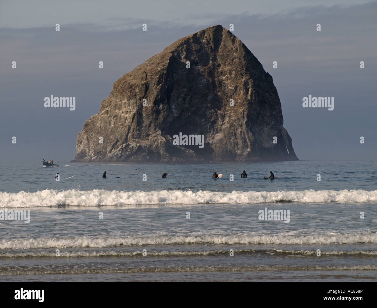 Surfers dressed in wetsuits wait for large waves in front of Haystack ...