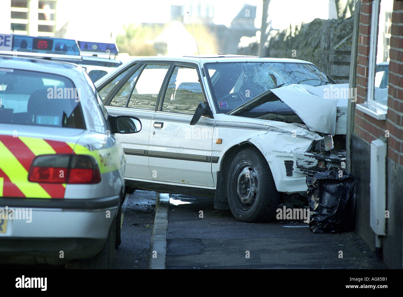 Crumpled front end of a car that has crashed into the wall of a house ...