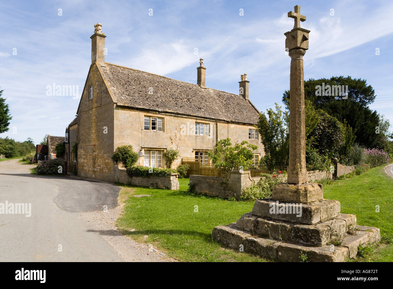 Farmhouse and medieval cross in the Cotswold village of Saintbury ...