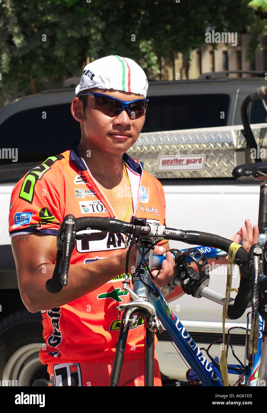 A young male cyclist in an orange cycling suit, sunglasses, and a white ...