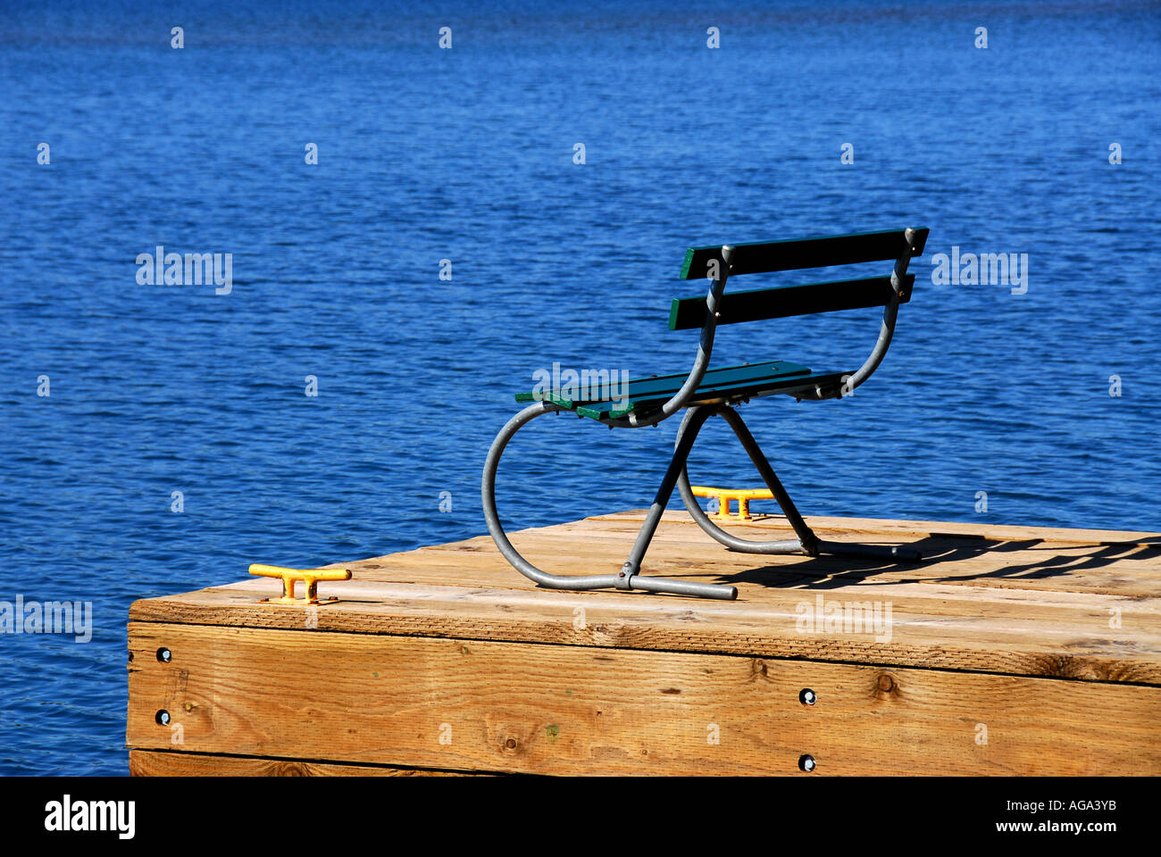 Empty bench on wood dock facing blue water Stock Photo - Alamy
