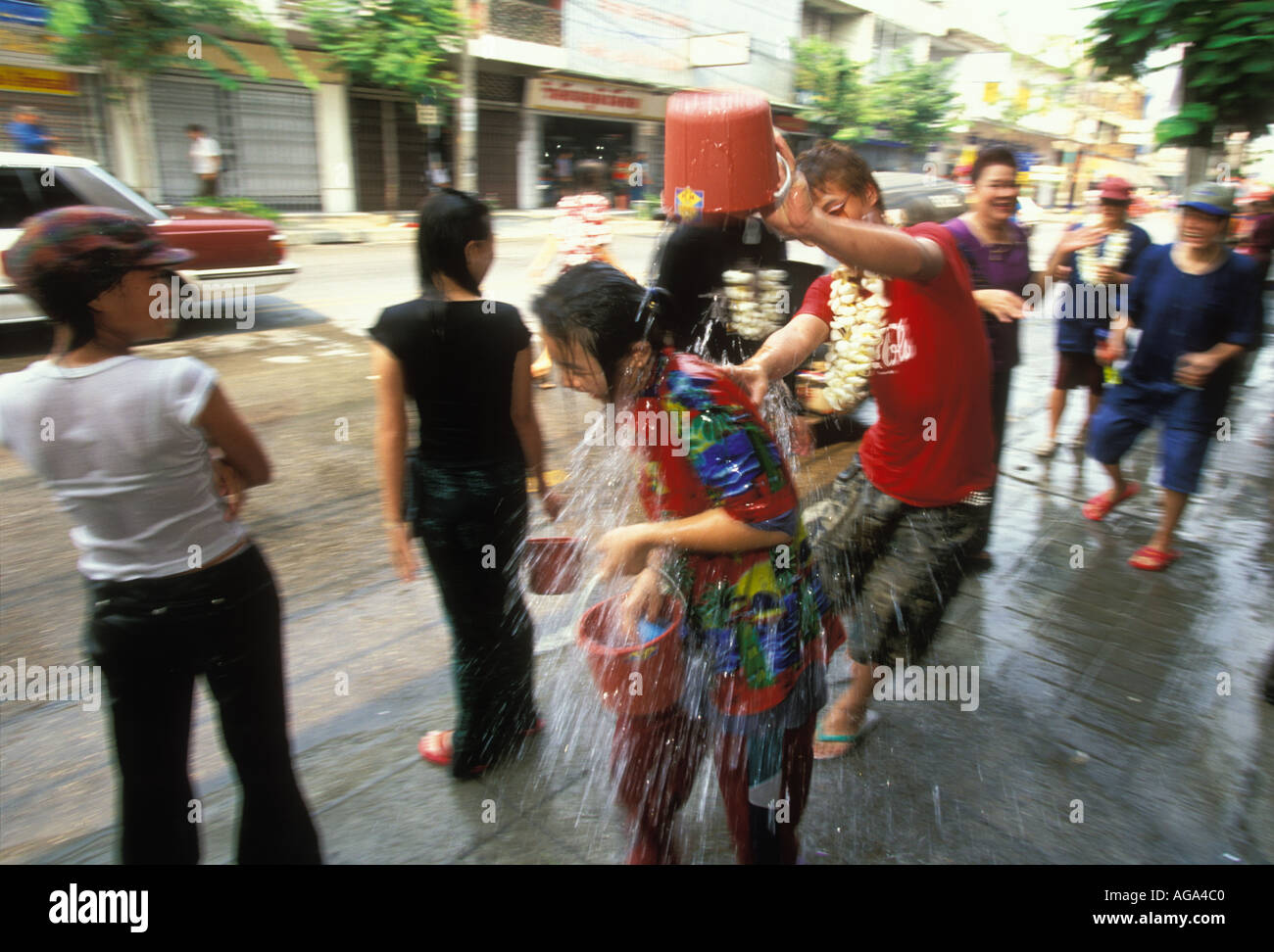 Emptying a bucket of water over a young woman at Songkran the Thai New ...
