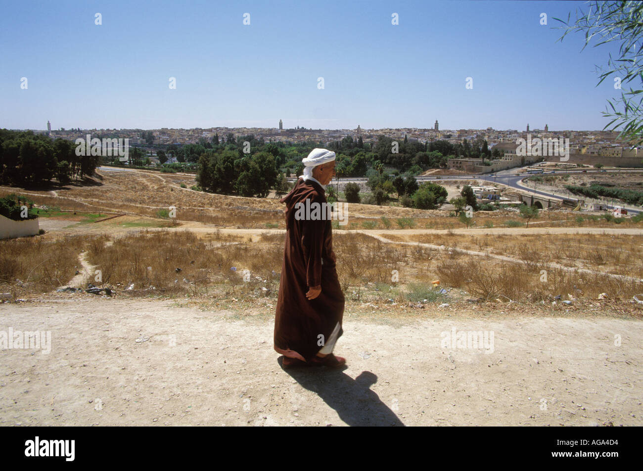 Man in turban and jellabah with a view of the city of Meknes in the ...