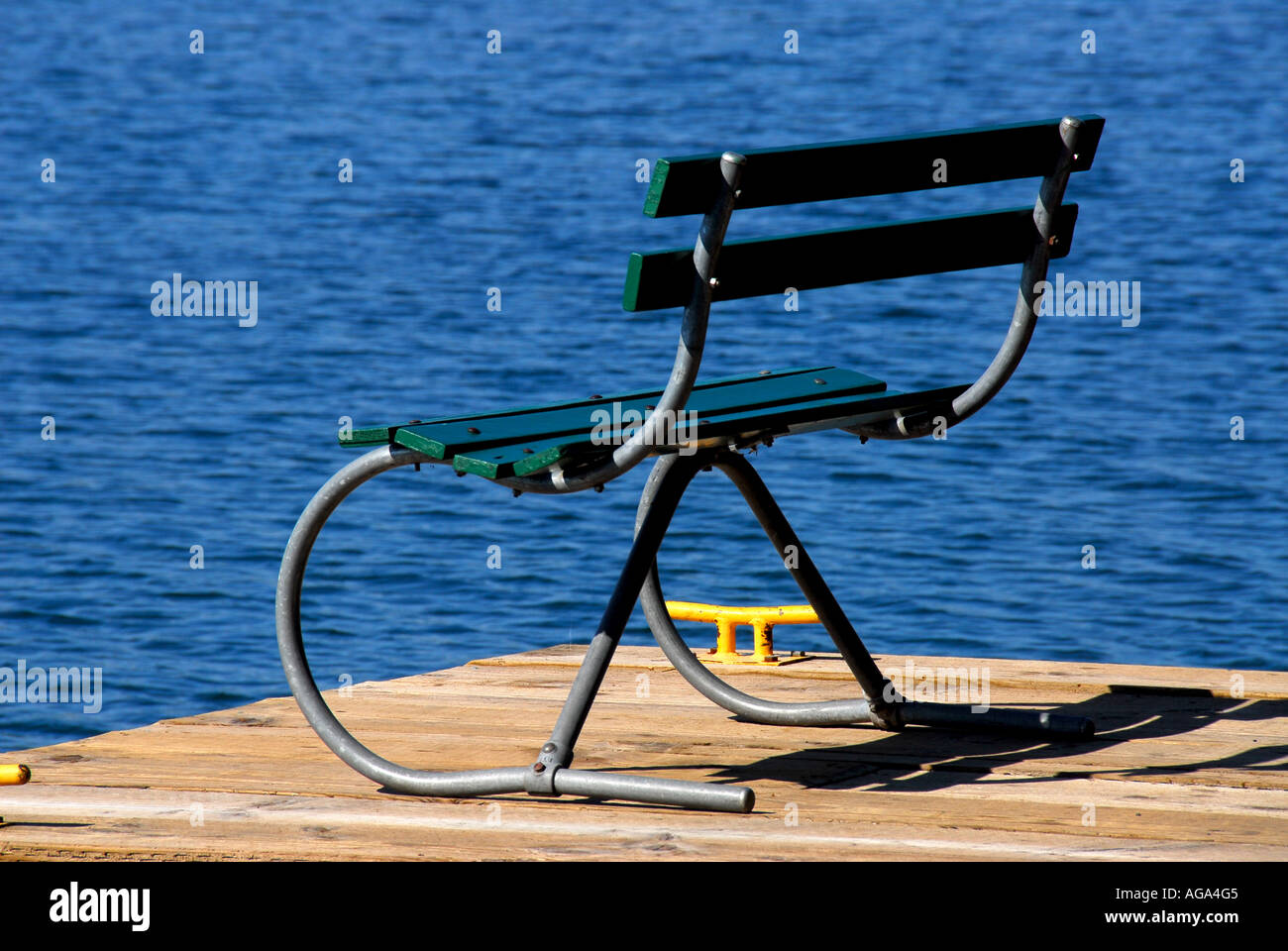 Empty bench on wood dock facing blue water Stock Photo - Alamy