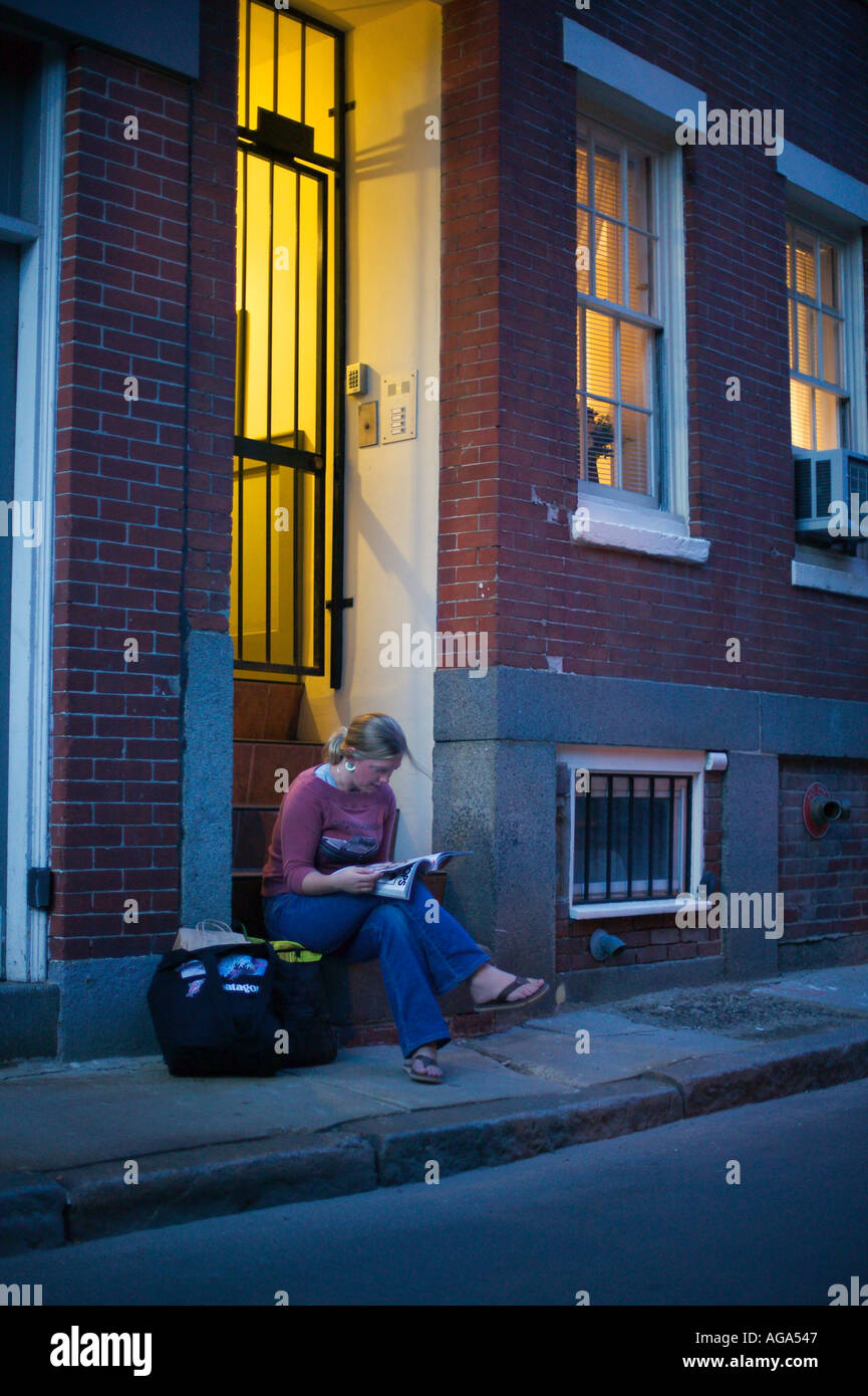 Woman sitting on front stoop of brownstone residence building in the ...