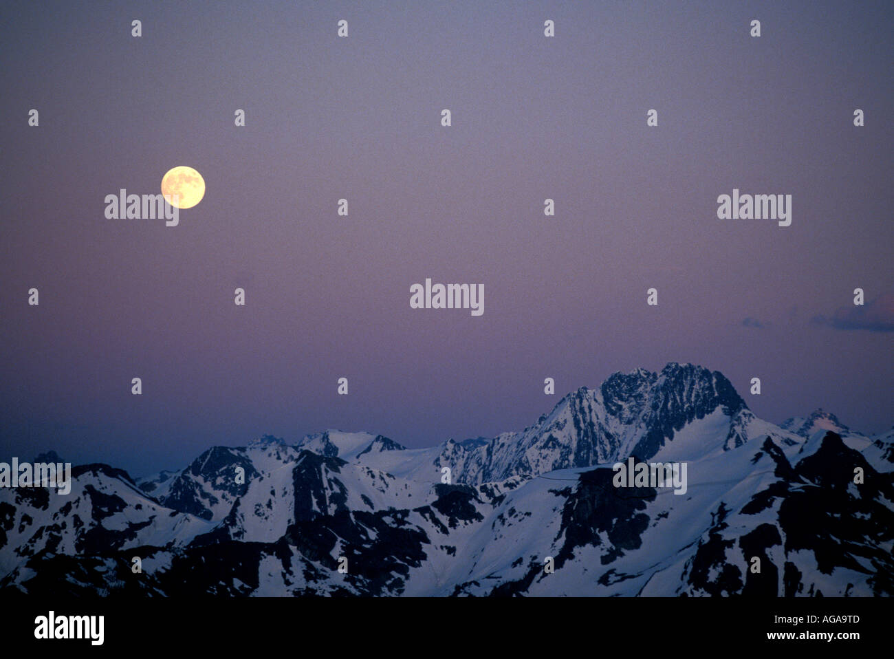 Moon twilight over snowy snow capped mountains Stock Photo - Alamy