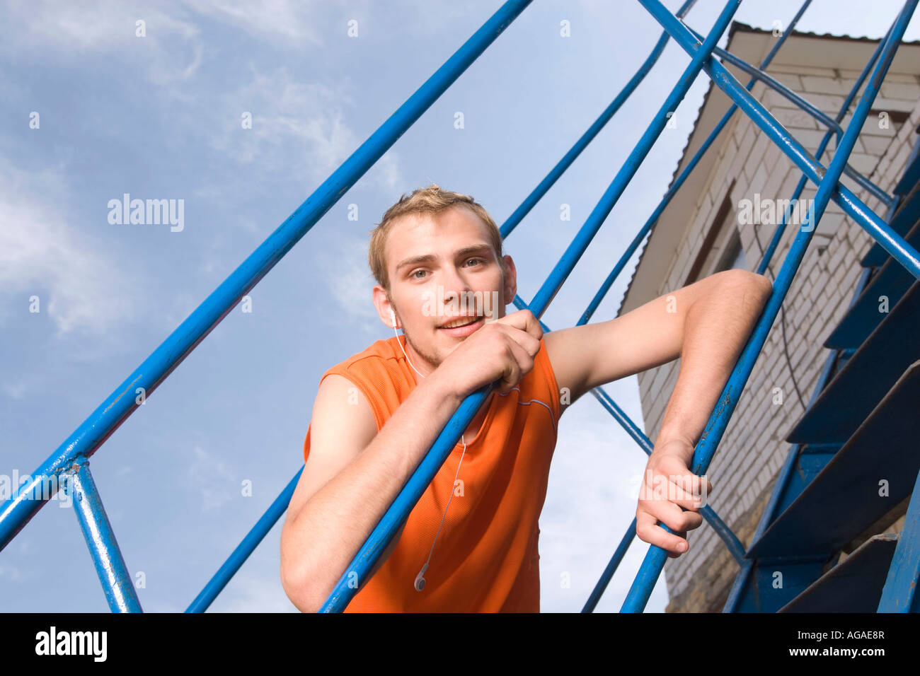 portrait of young man leaning on railing listening to music on mp3 ...
