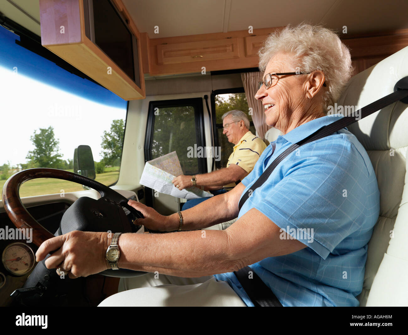 Senior adult woman driving RV and smiling while man reads map in ...