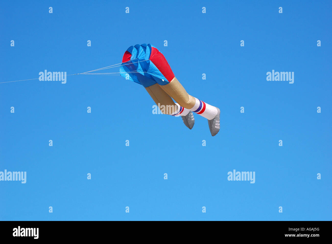 kite or balloon of lower half of a body flying alone against a blue sky ...