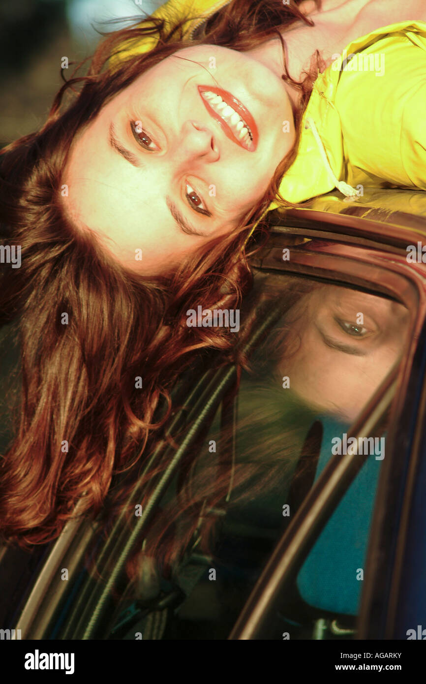 a woman laughing girl happy is on the top of a car her face is ...