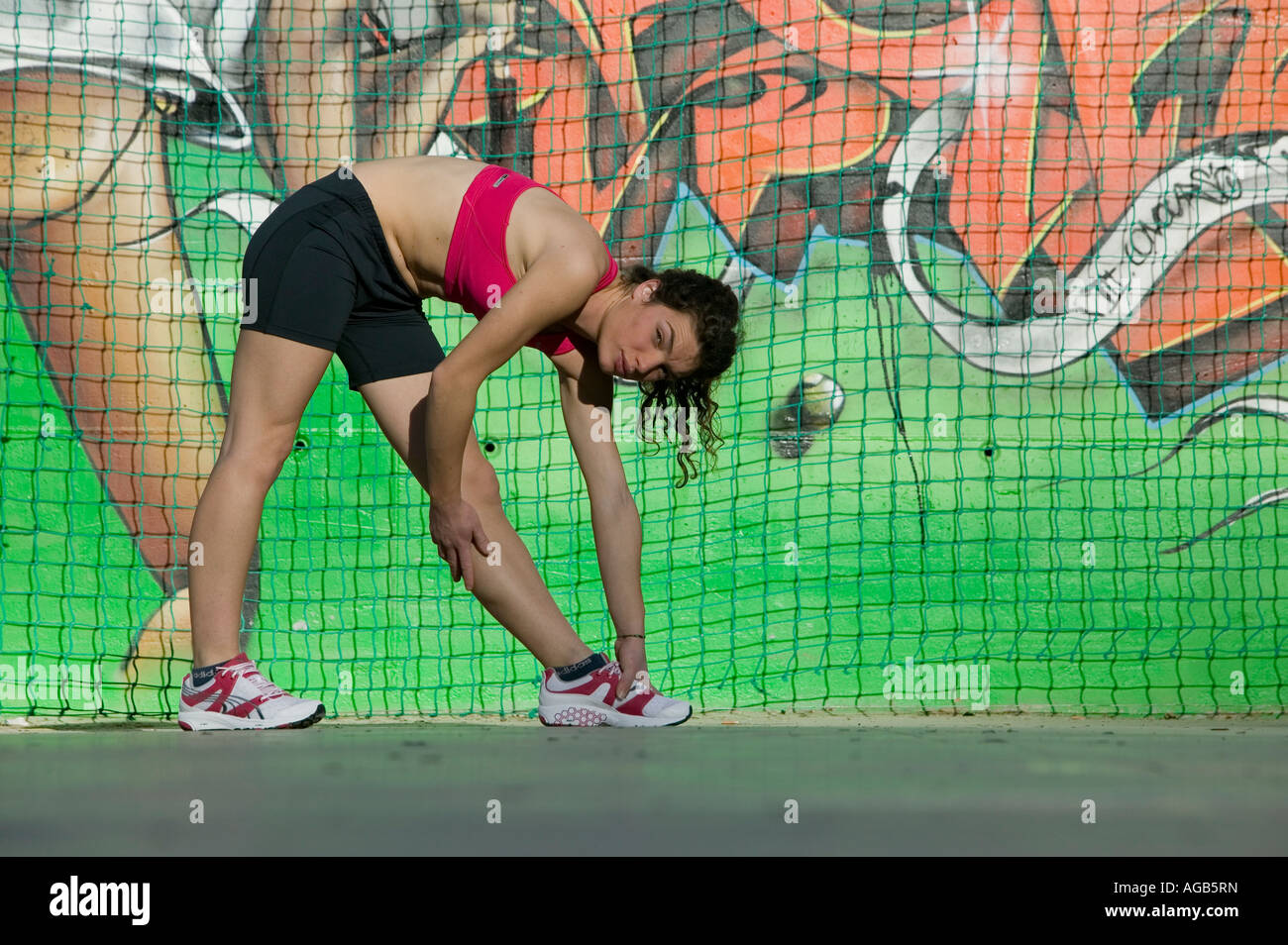Female runner stretching in front of grafitti covered wall Stock Photo ...