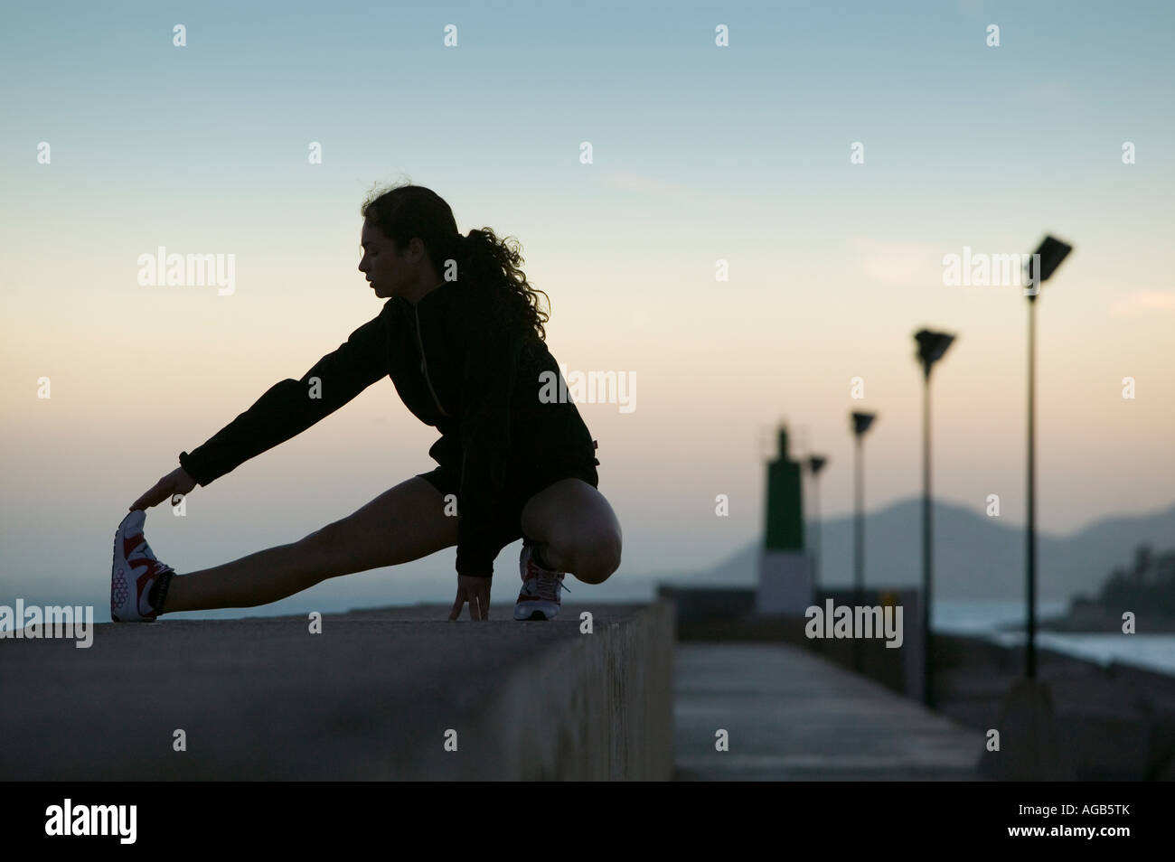 Female runner stretching on harbour wall Stock Photo - Alamy