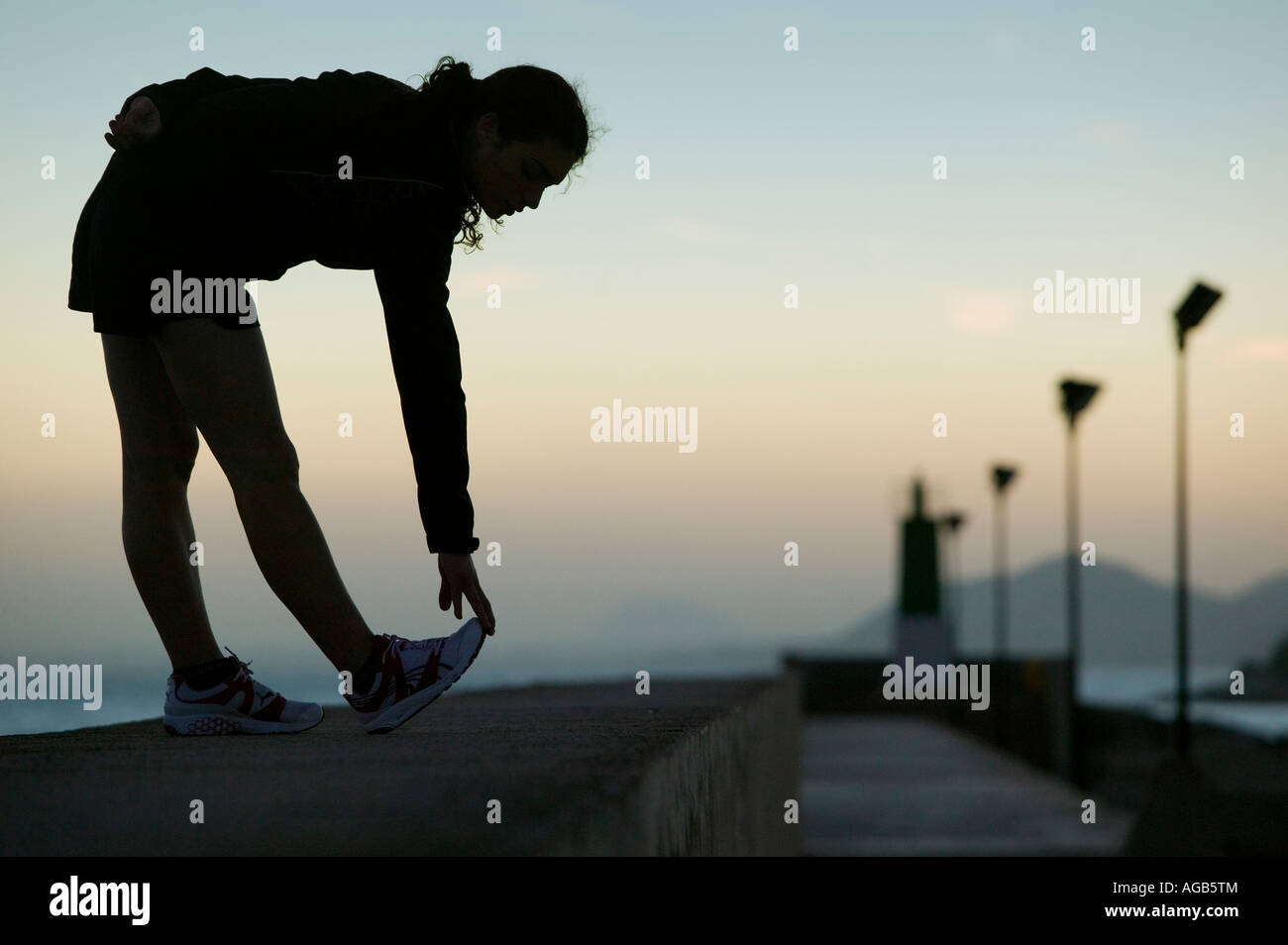 Female runner stretching on harbour wall Stock Photo - Alamy