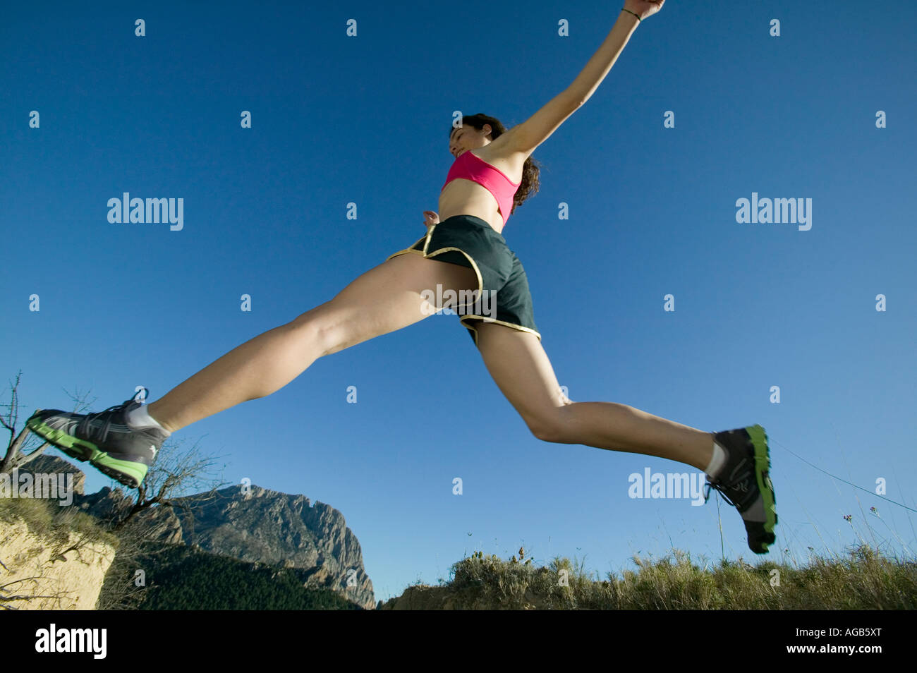 Female runner leaping with mountain background Stock Photo - Alamy