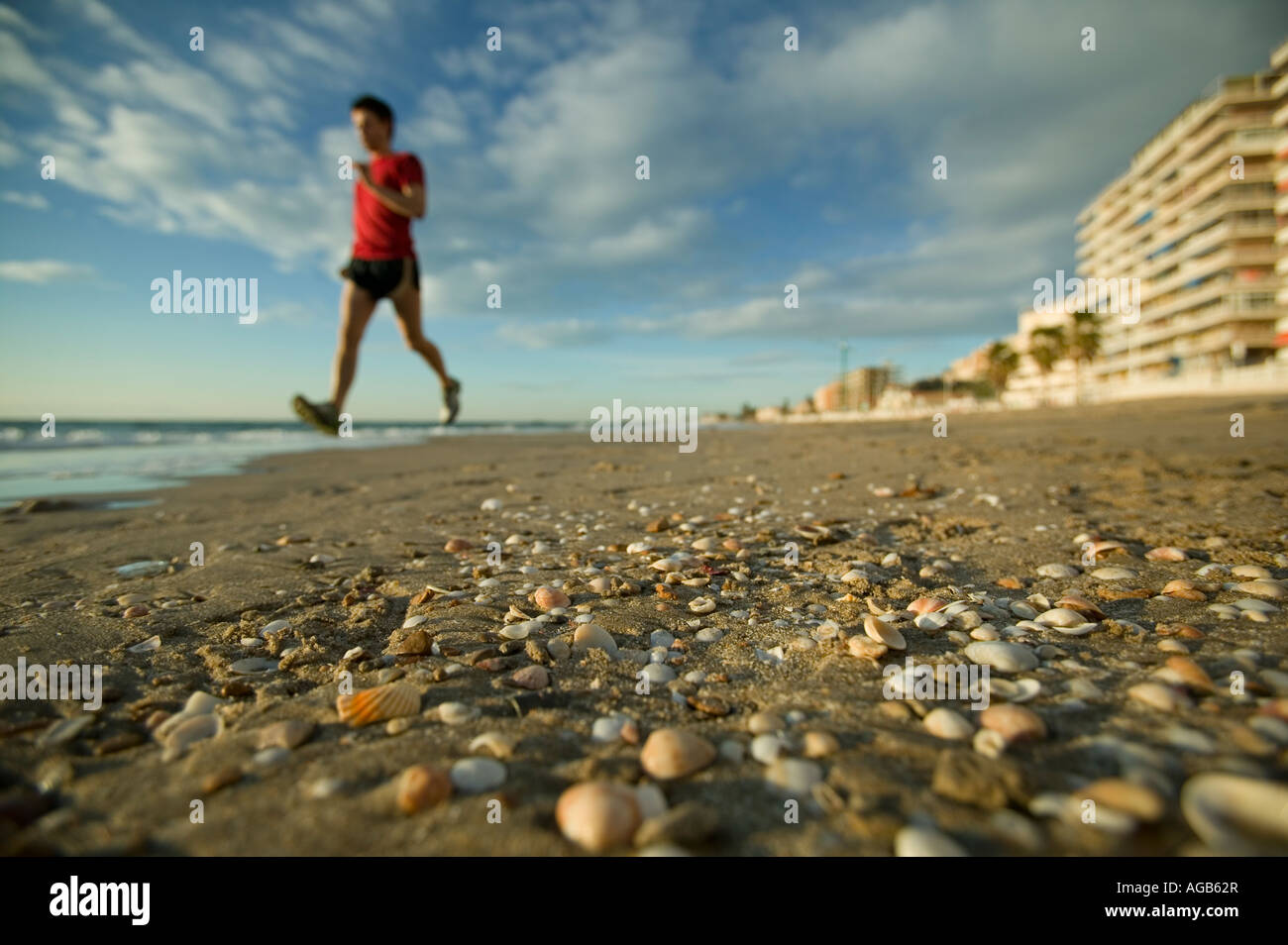 Male runner on beach with shells in foreground Stock Photo - Alamy