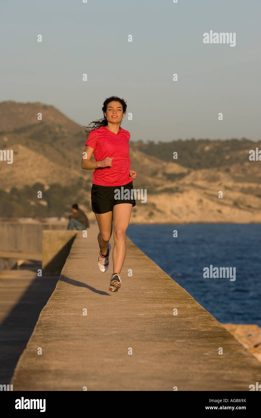Female runner on harbour wall Stock Photo - Alamy