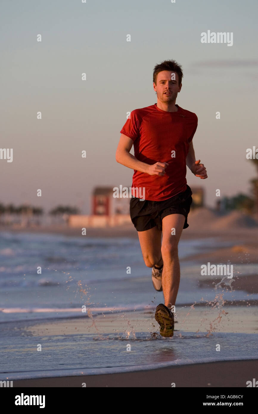 Male runner on beach at sunrise Stock Photo - Alamy