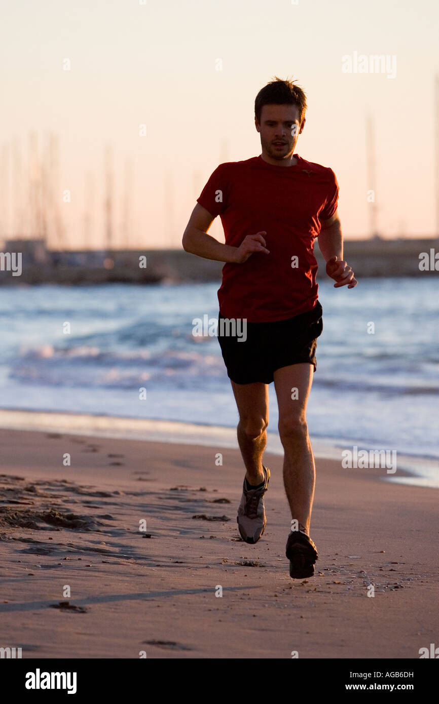 Male runner on beach at sunrise Stock Photo - Alamy