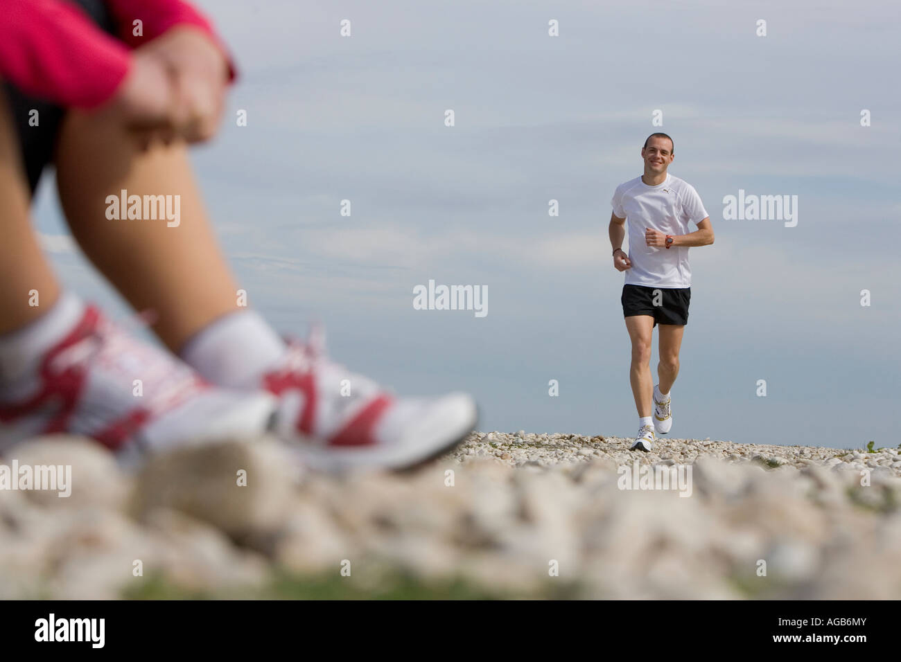 Male jogger running to seated partner Stock Photo - Alamy