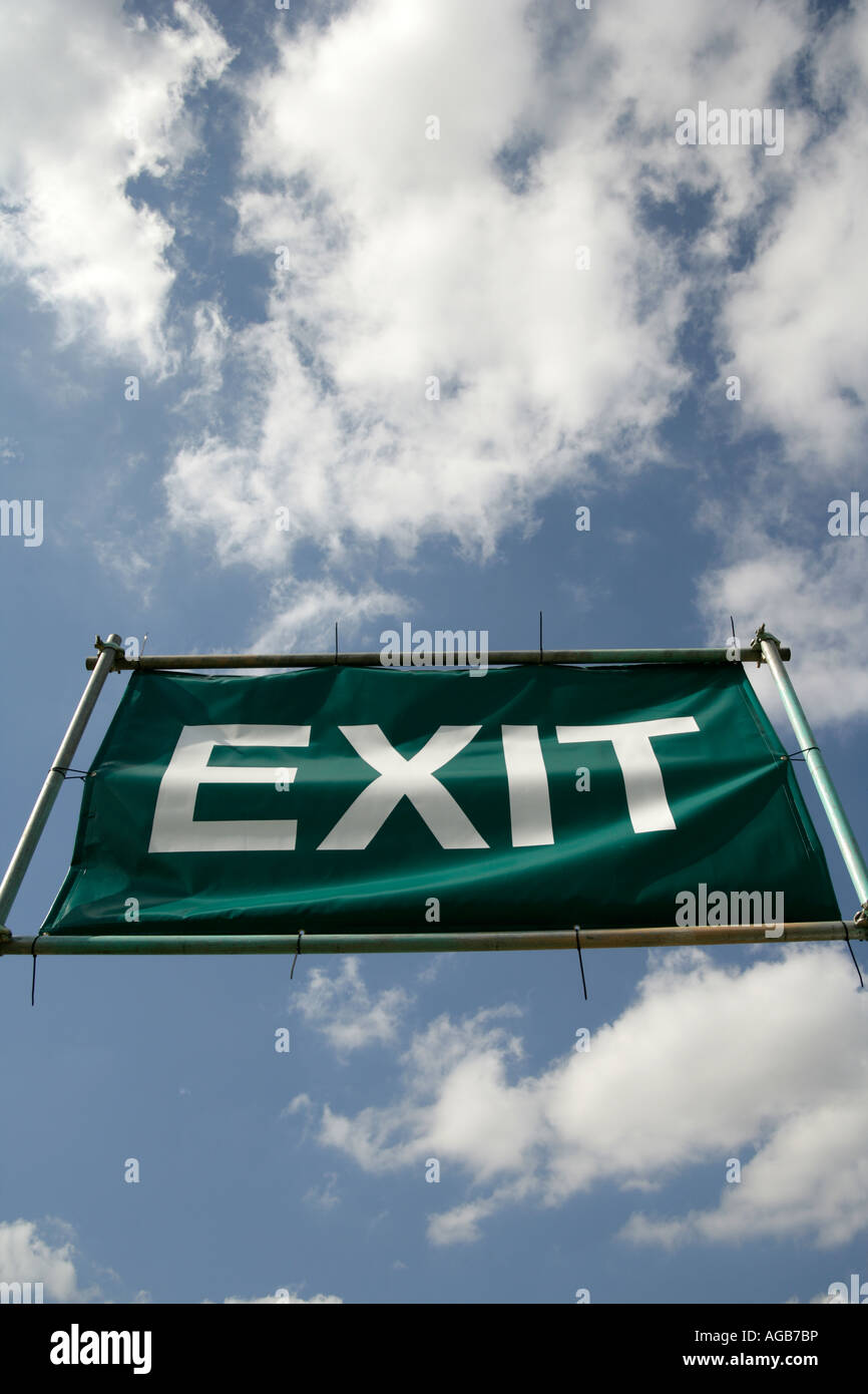Green exit sign erected on scaffolding on a background of blue sky and ...