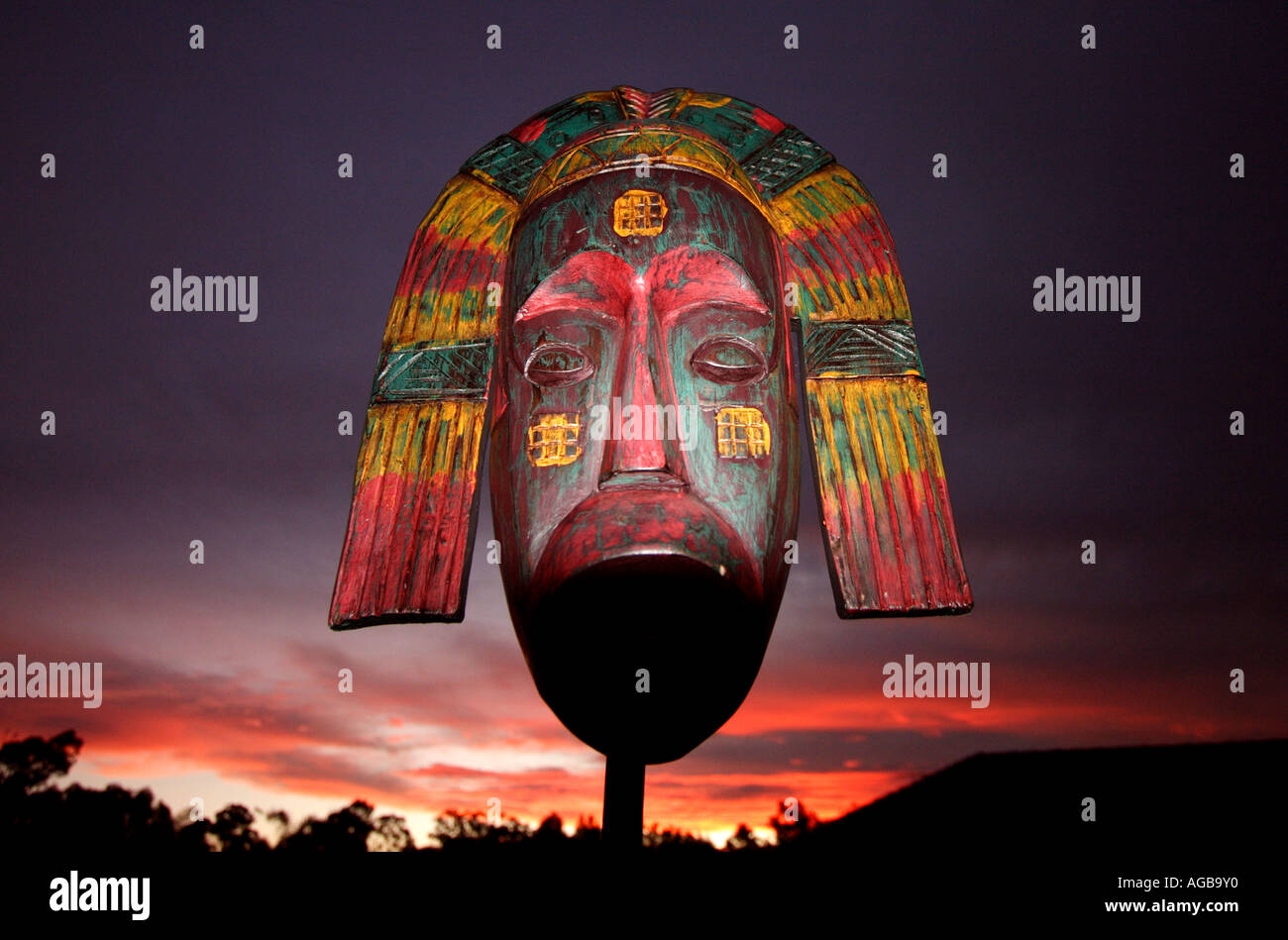 HAND CARVED WOODEN MASK AGAINST A RED SUNSET SKY HORIZONTAL BAPDB8174 ...