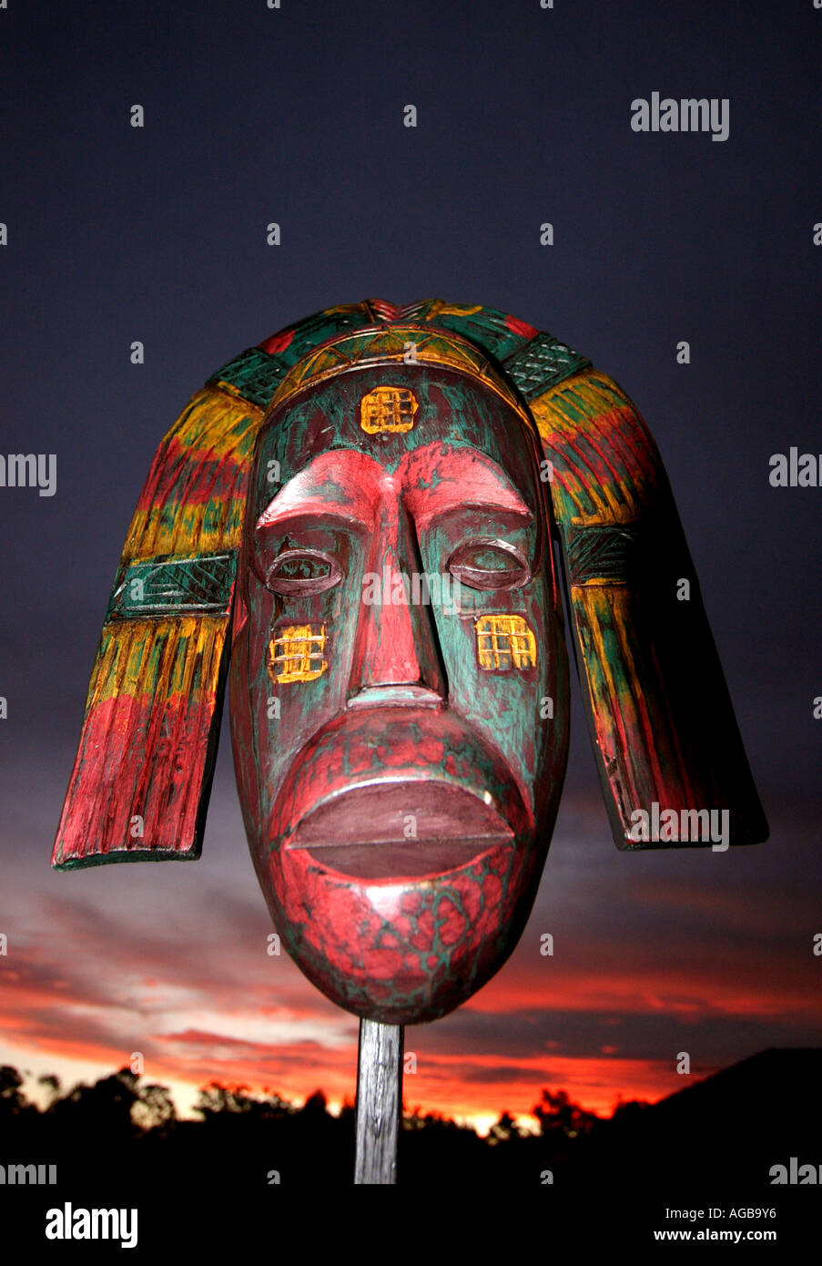 HAND CARVED WOODEN MASK AGAINST A RED SUNSET SKY VERTICAL BAPDB8176 ...