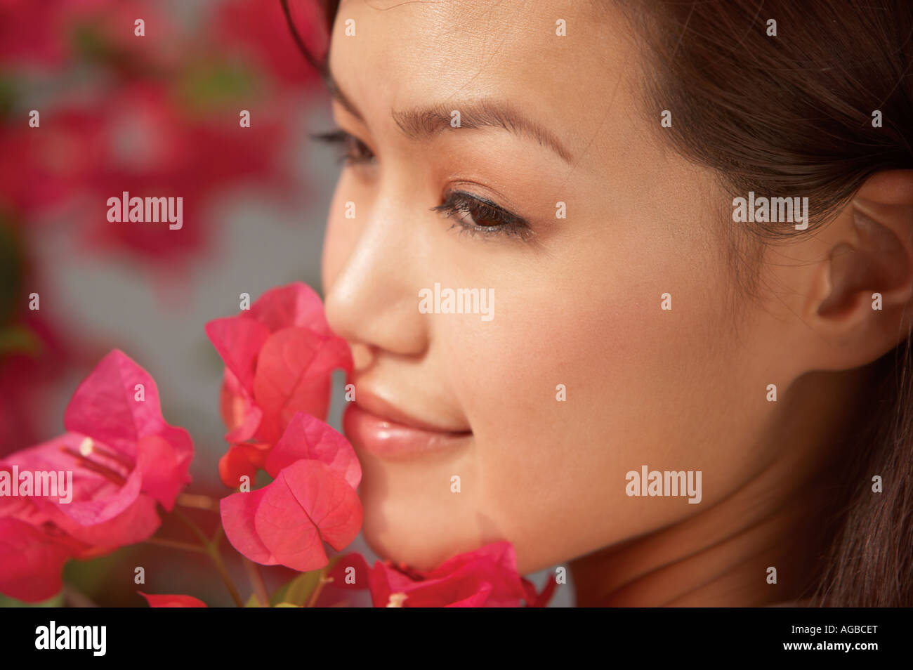 Young woman standing near flower, turning back and smiling, close up ...