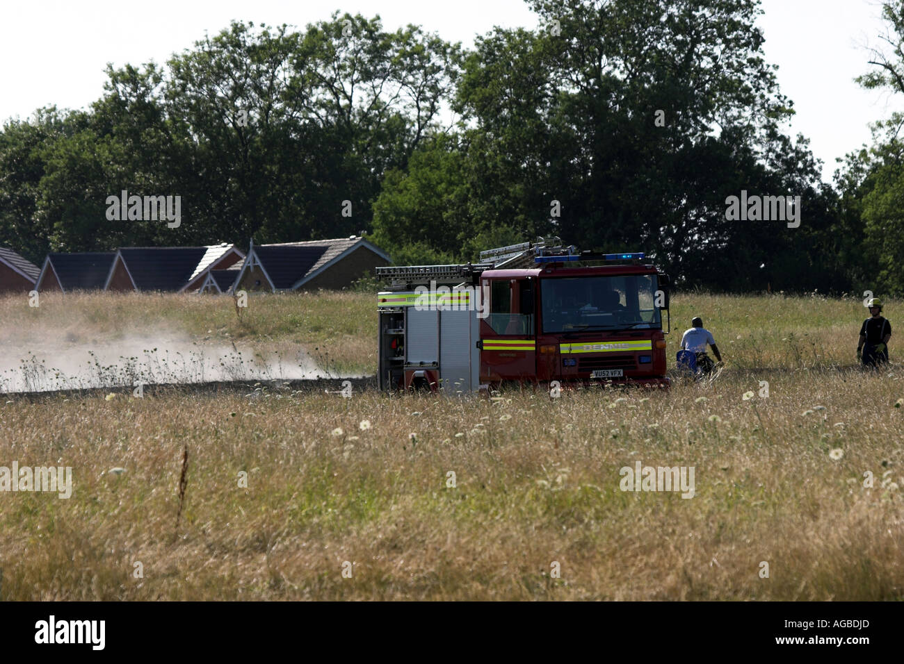 Firemen and fire engine next to a smoldering fire Stock Photo - Alamy