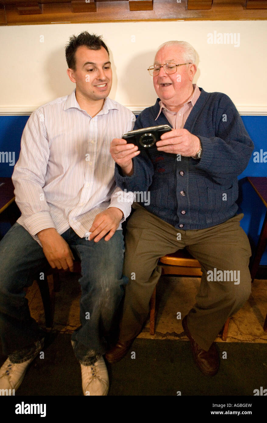 Old man in pub showing young man how to use his sony PSP playstation ...