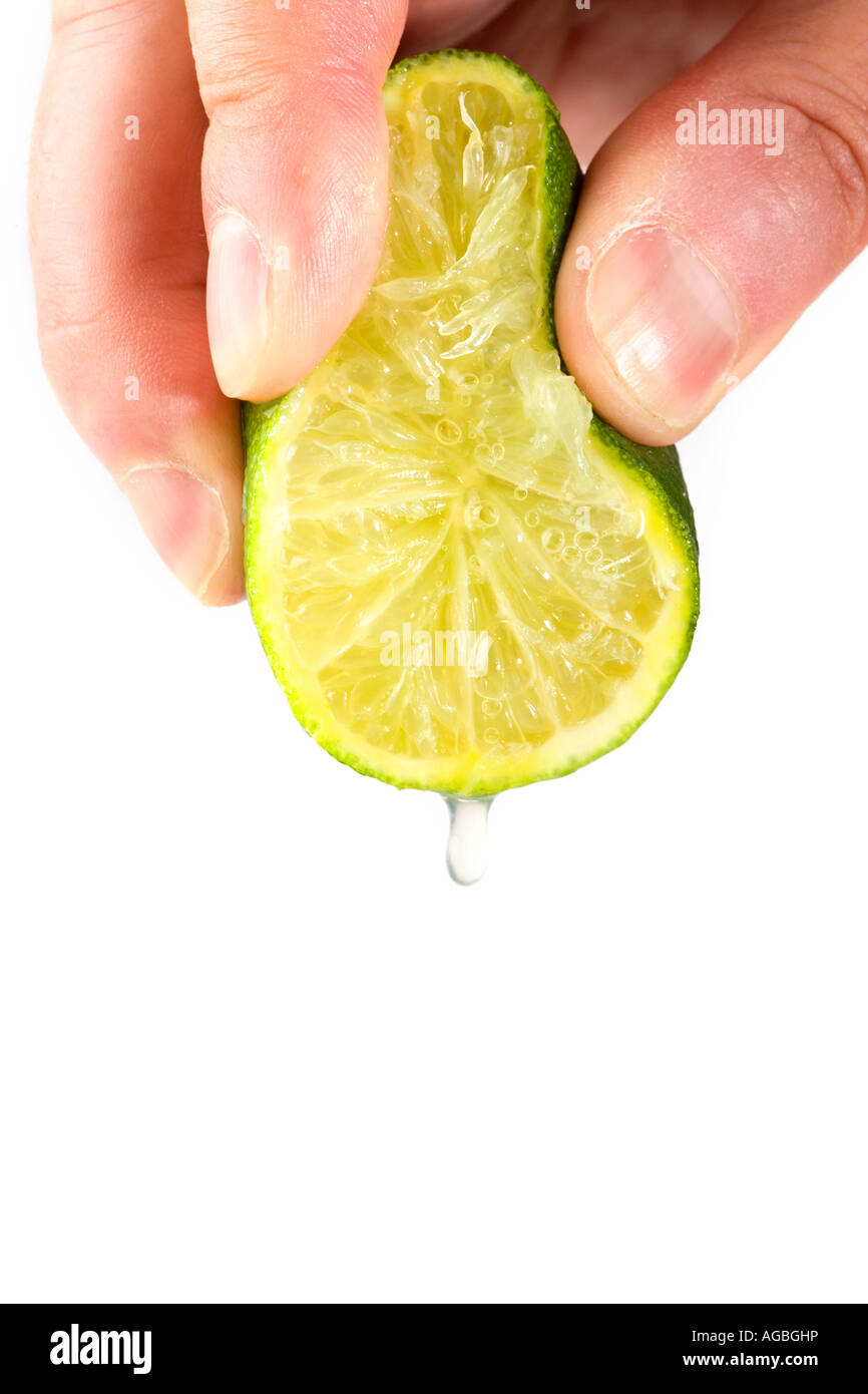 Male hand squeezing a lemon lime with droplets Stock Photo - Alamy