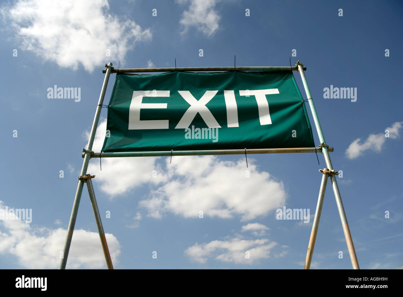 Green exit sign erected on scaffolding on a background of blue sky and ...