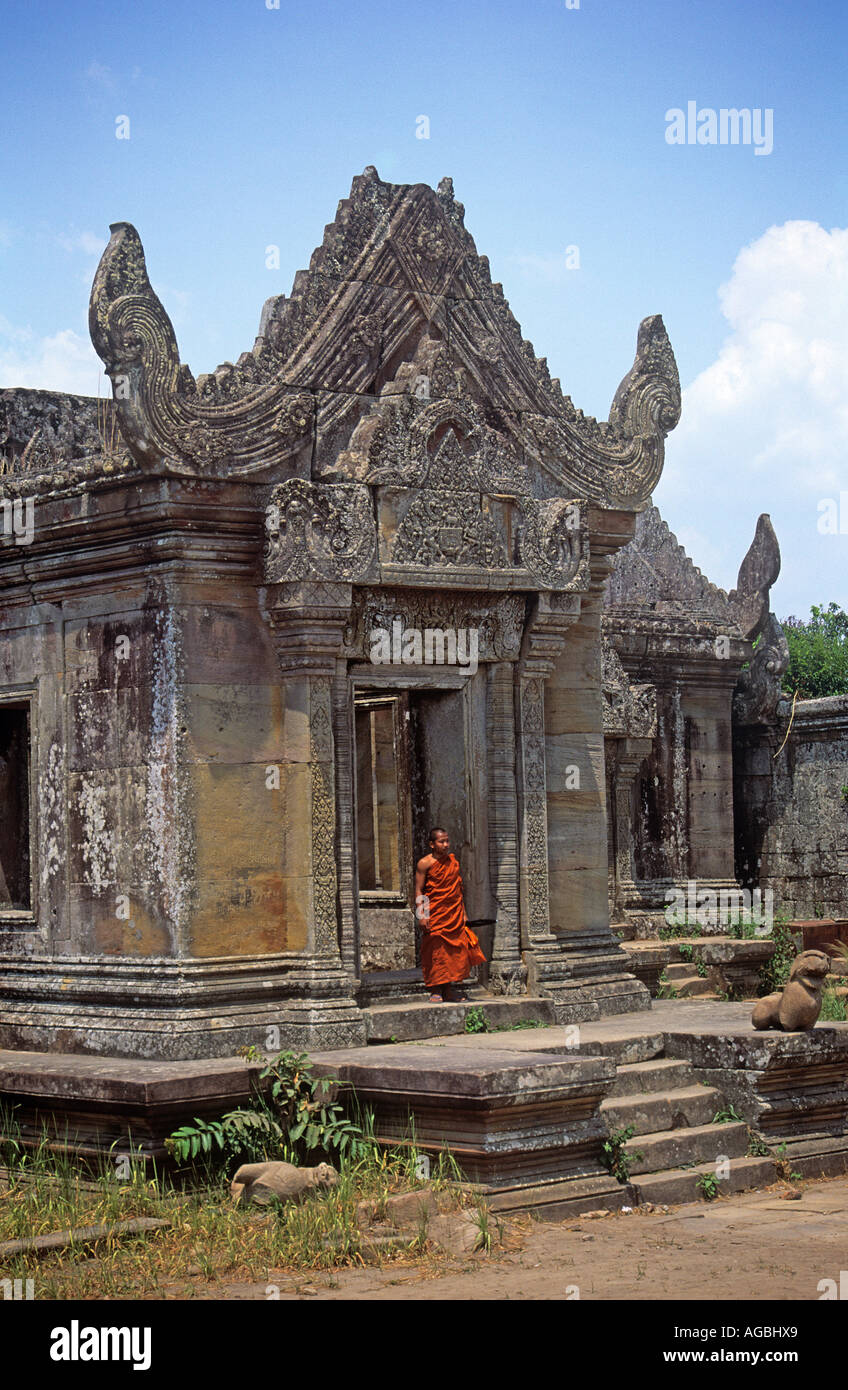 An orange clad monk seated outside a section of the Khmer ruins of Khao ...