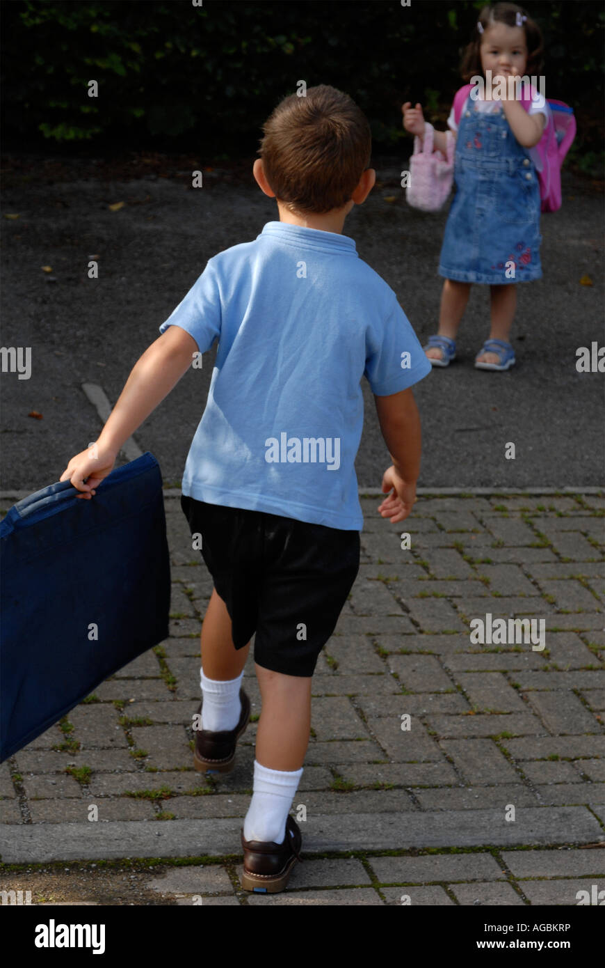 Rear view of a young boy wearing school uniform with a little girl in ...