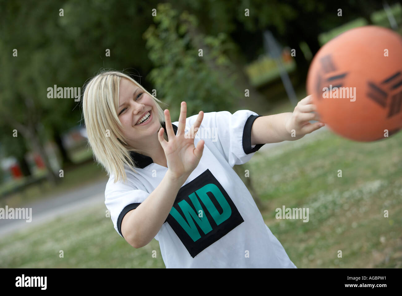 Girl throwing netball and smiling Stock Photo - Alamy