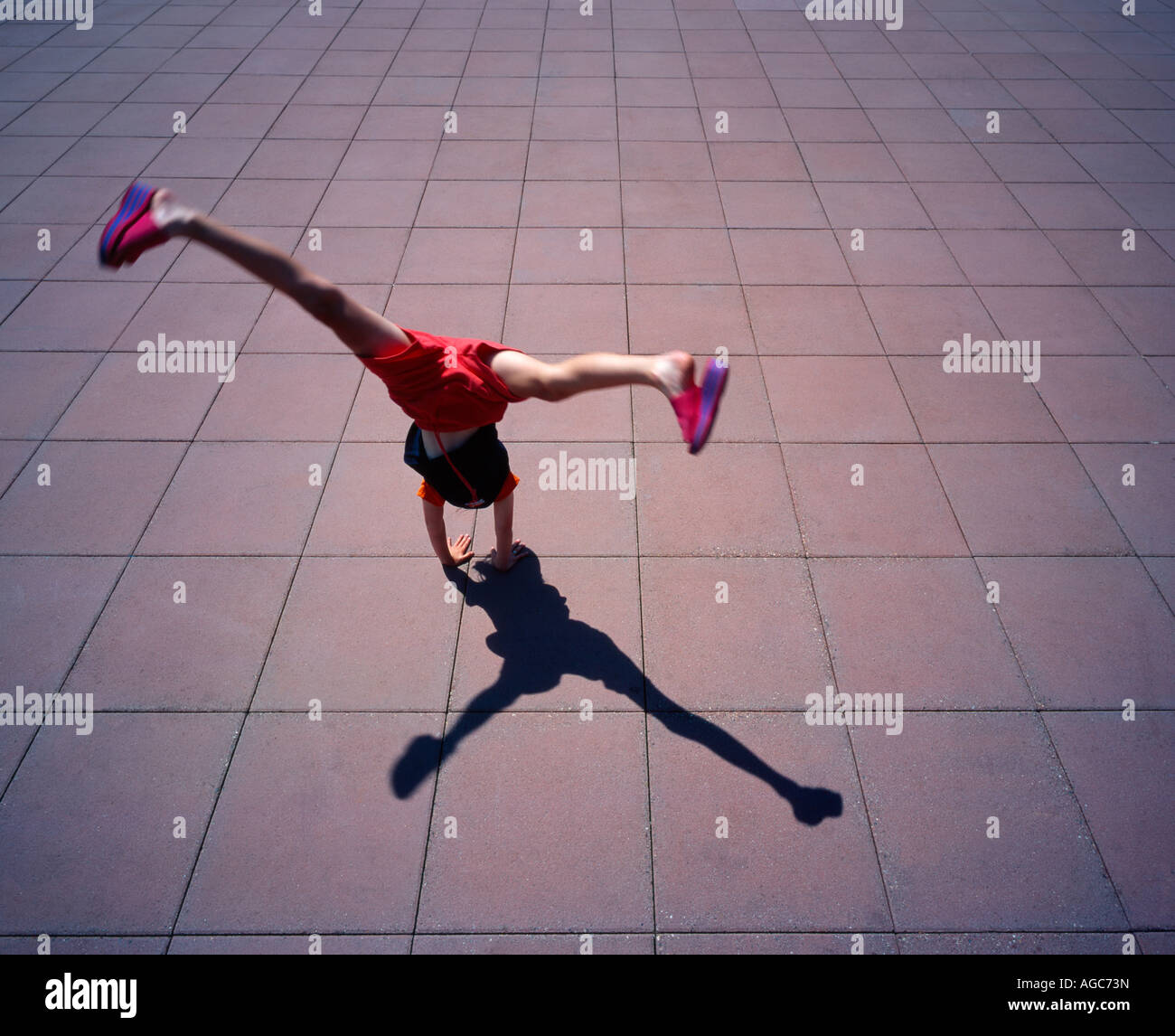 a young girl does a handstand while cartwheeling on pavement Stock ...