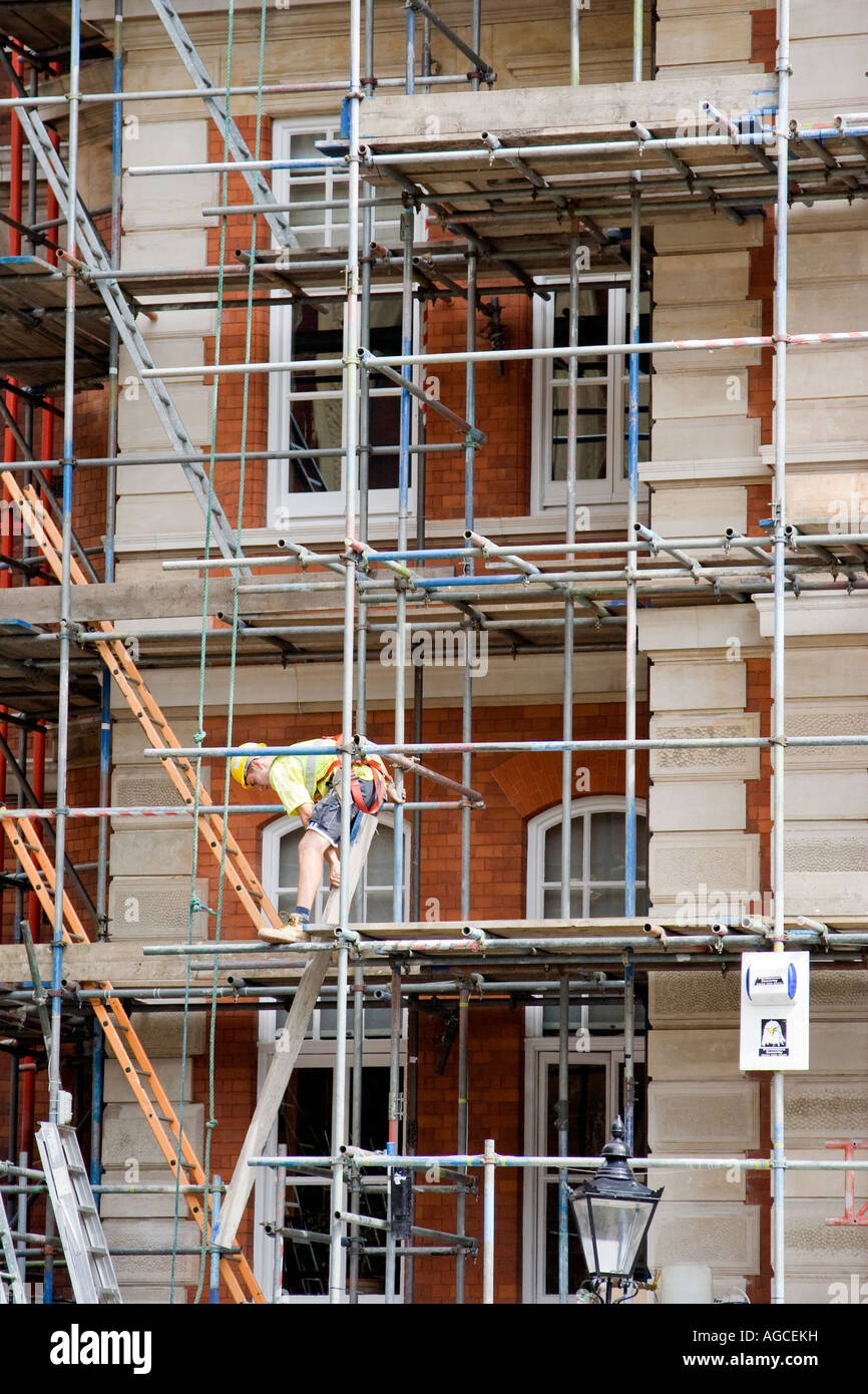 Man working on a scaffold repairing a classic building in London city ...